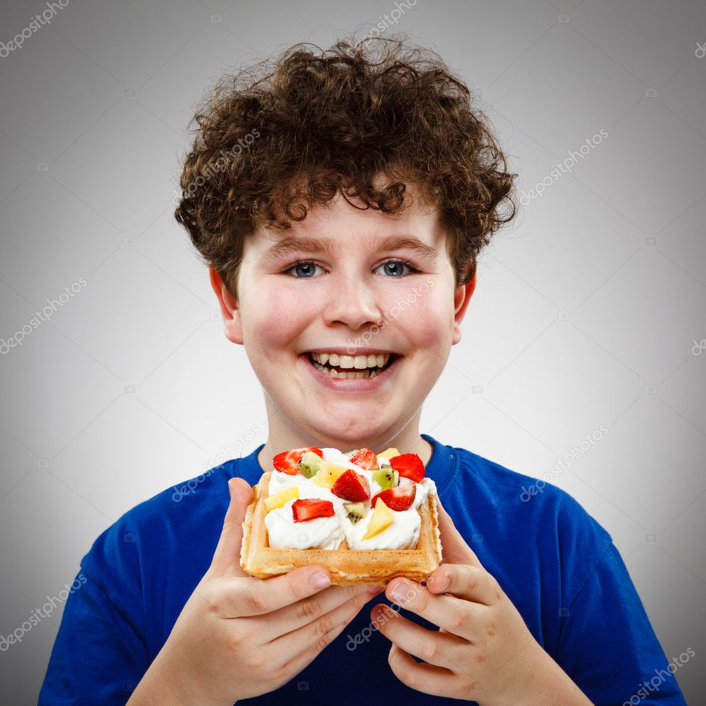Boy eating cake with cream and fruits — Stock Photo © gbh007 #9534148