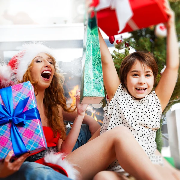 Young happy family near a Christmas tree at home holding gift an ...