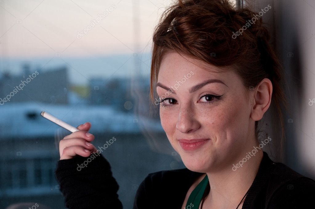 Beautiful young woman smoking on evening window. Stock Photo by ©markin ...