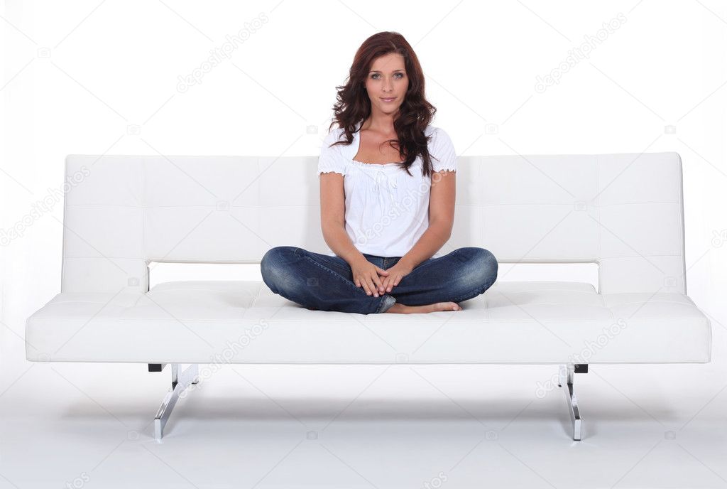 Woman sitting cross legged on a white sofa Stock Photo by ...