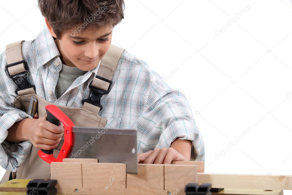 Young boy dressed as a carpenter sawing wood Stock Photo by ...