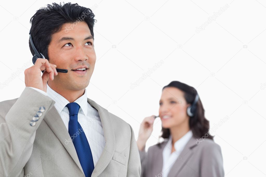 Call center agent with headset and colleague behind him Stock Photo by ...