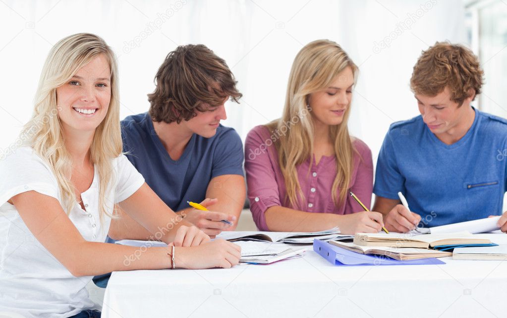 A study group working hard as one girl smiles and looks at the c Stock ...